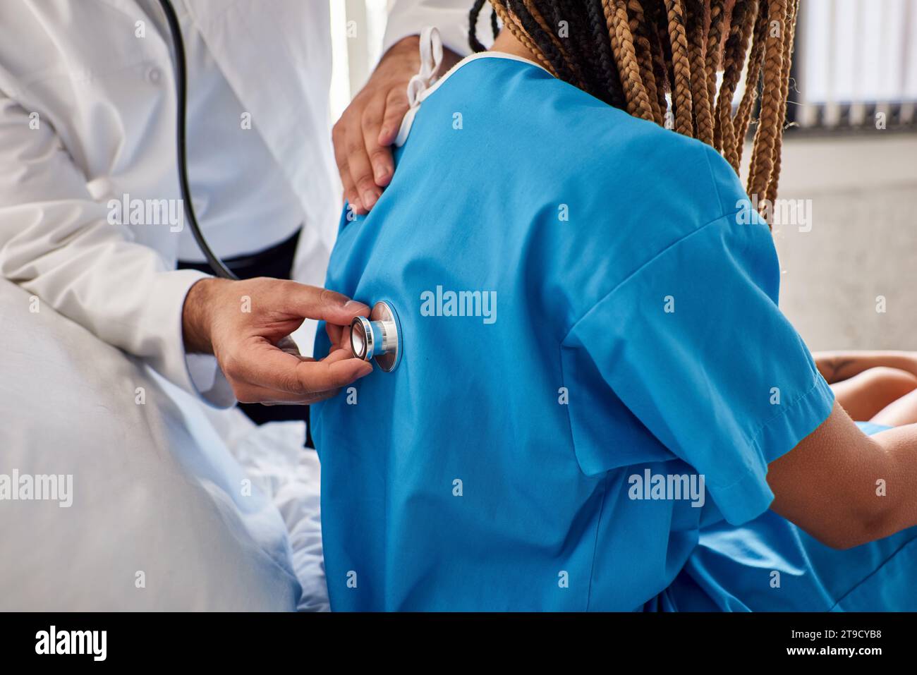 young indian doctor examining breath of his african american patient ...