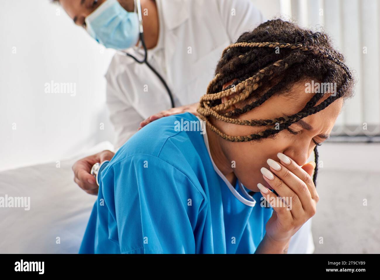 young indian doctor examining breath of ill african american patient ...