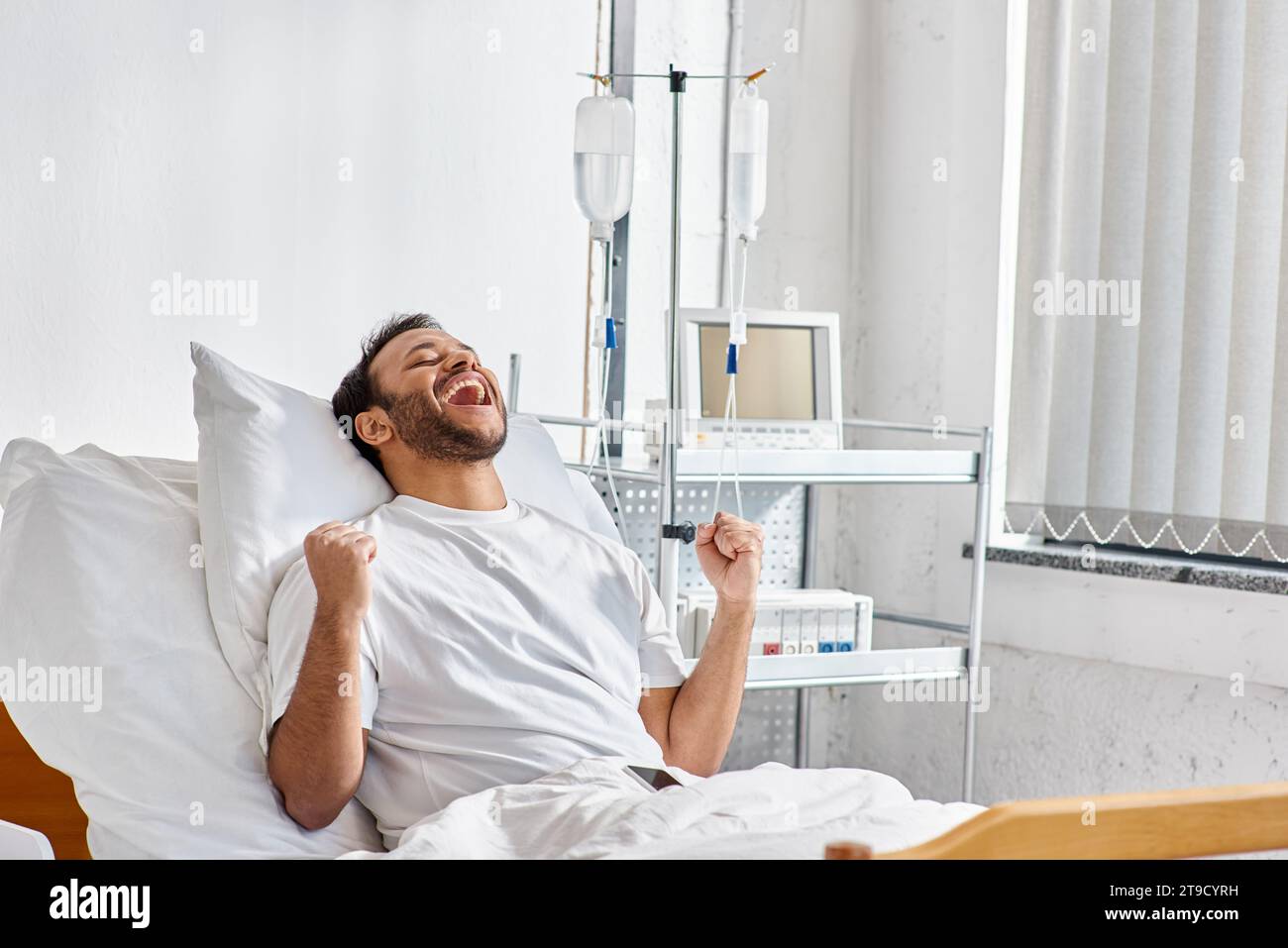 young happy indian patient cheering and gesturing actively while in ...