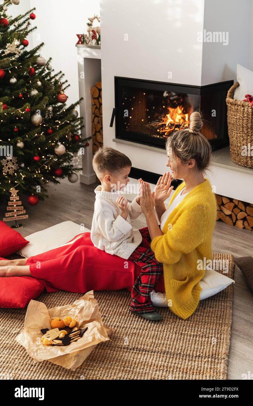 Woman and her little son play a hand-clapping game beside a glowing ...