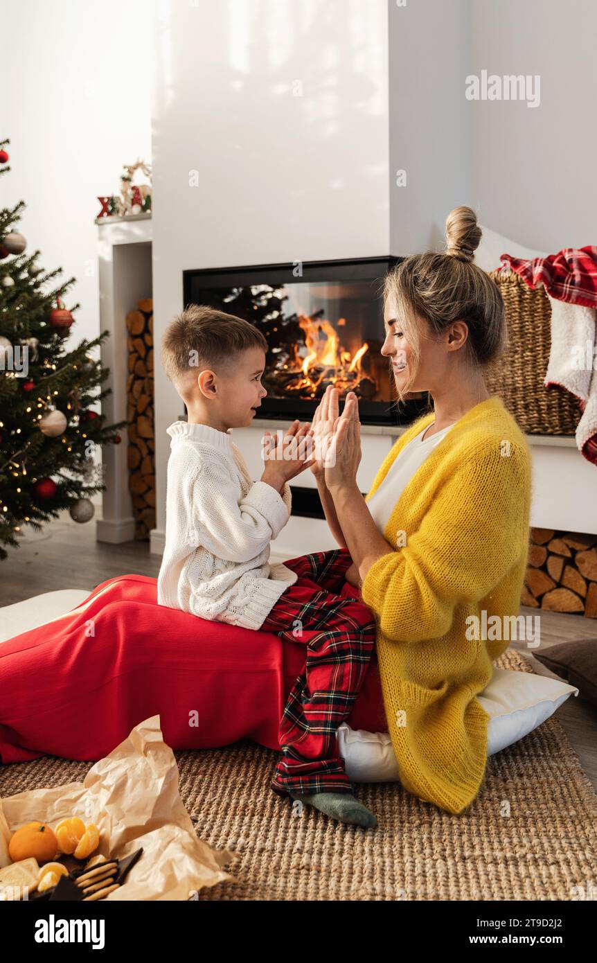 Woman and her little son play a hand-clapping game beside a glowing ...