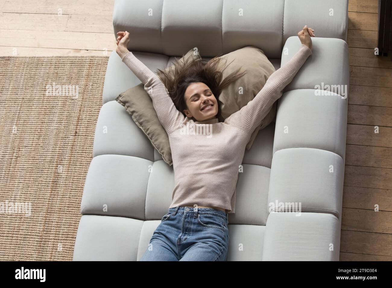 Well rested woman stretching lying on cozy sofa, top view Stock Photo ...