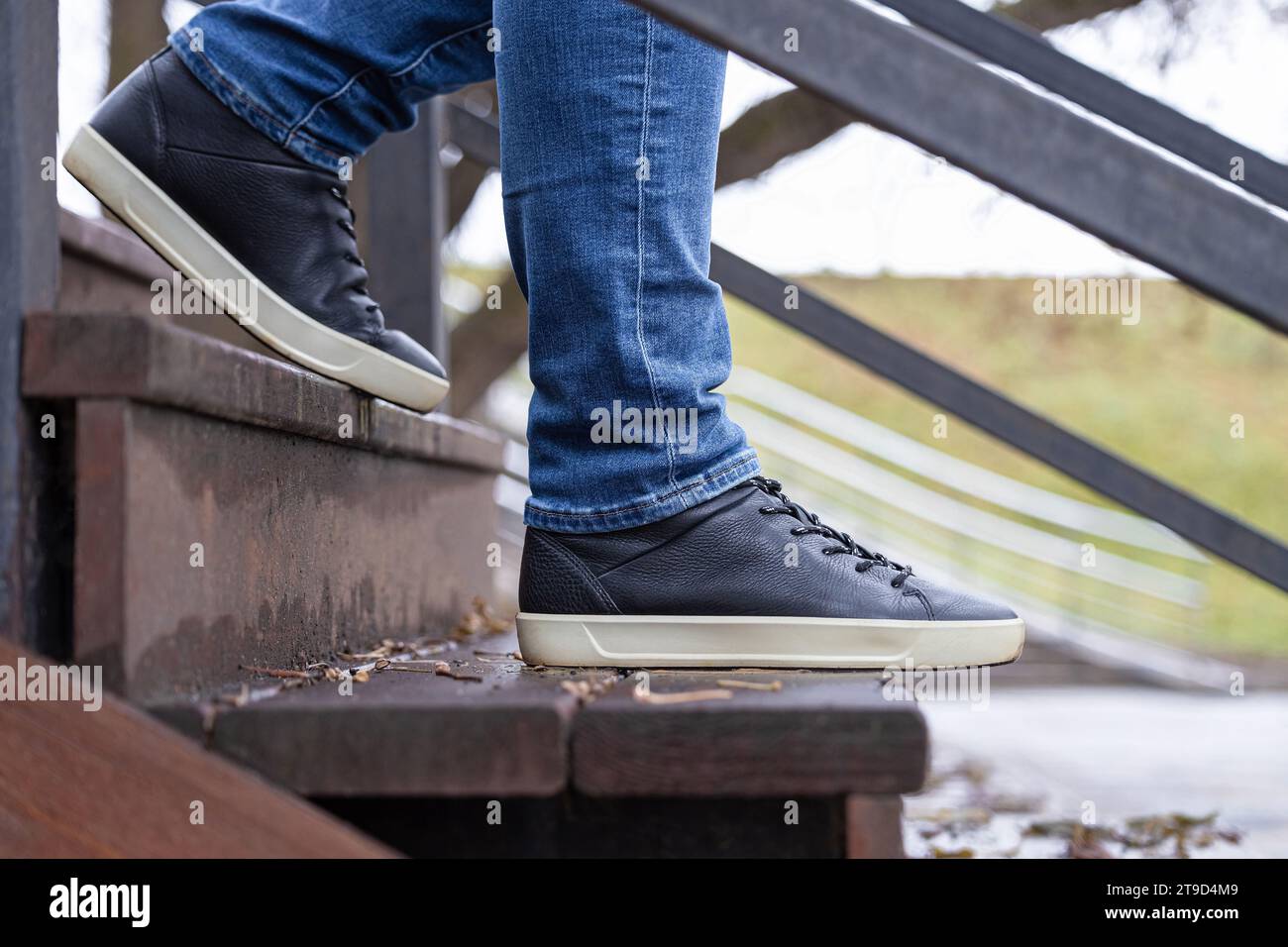 man going down wooden stairs in rainy weather. shoe steps on a wooden ...