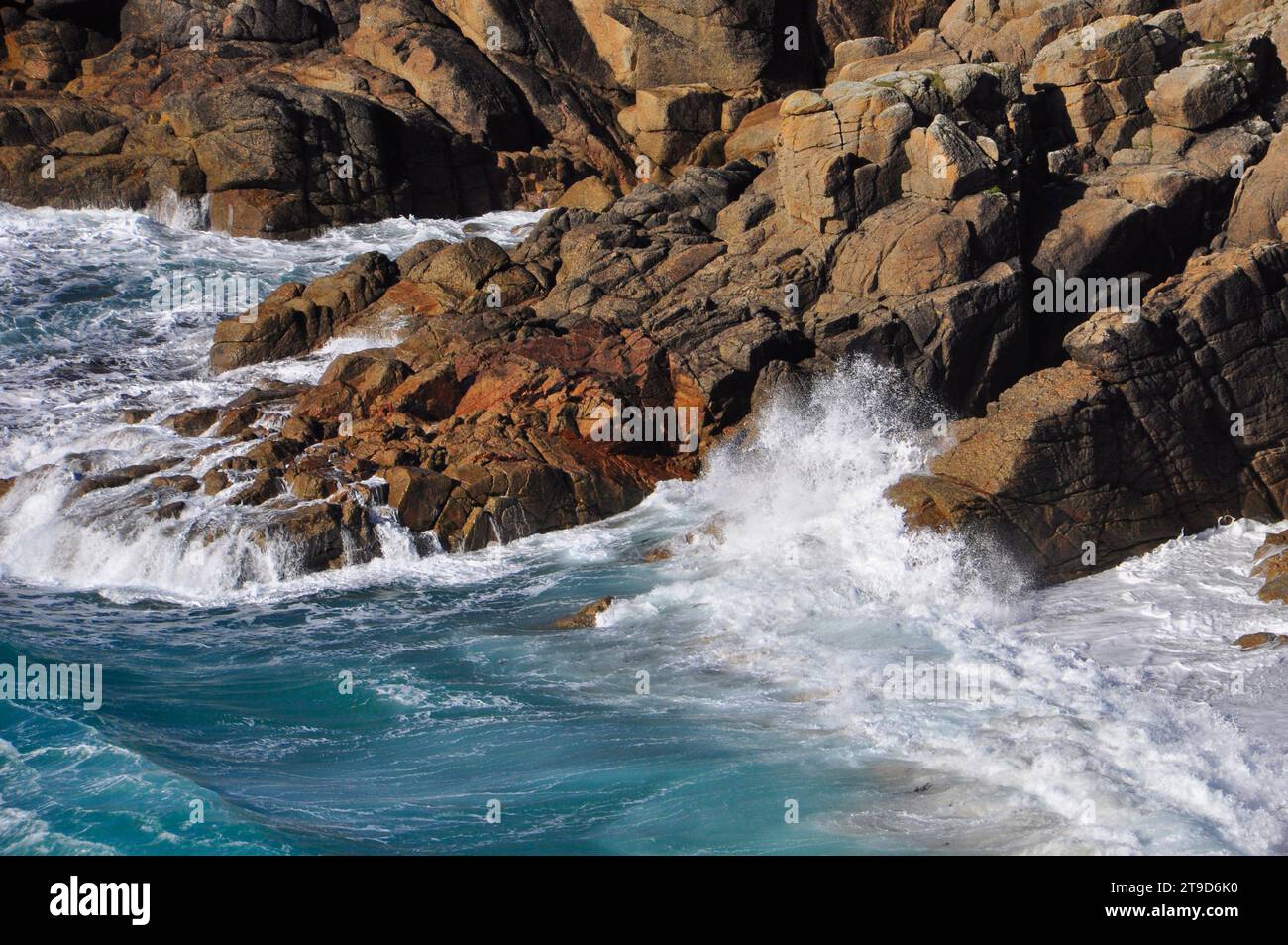 Waves crashing onto the sloping cliffs at sandy Porth Chapel Beach near ...