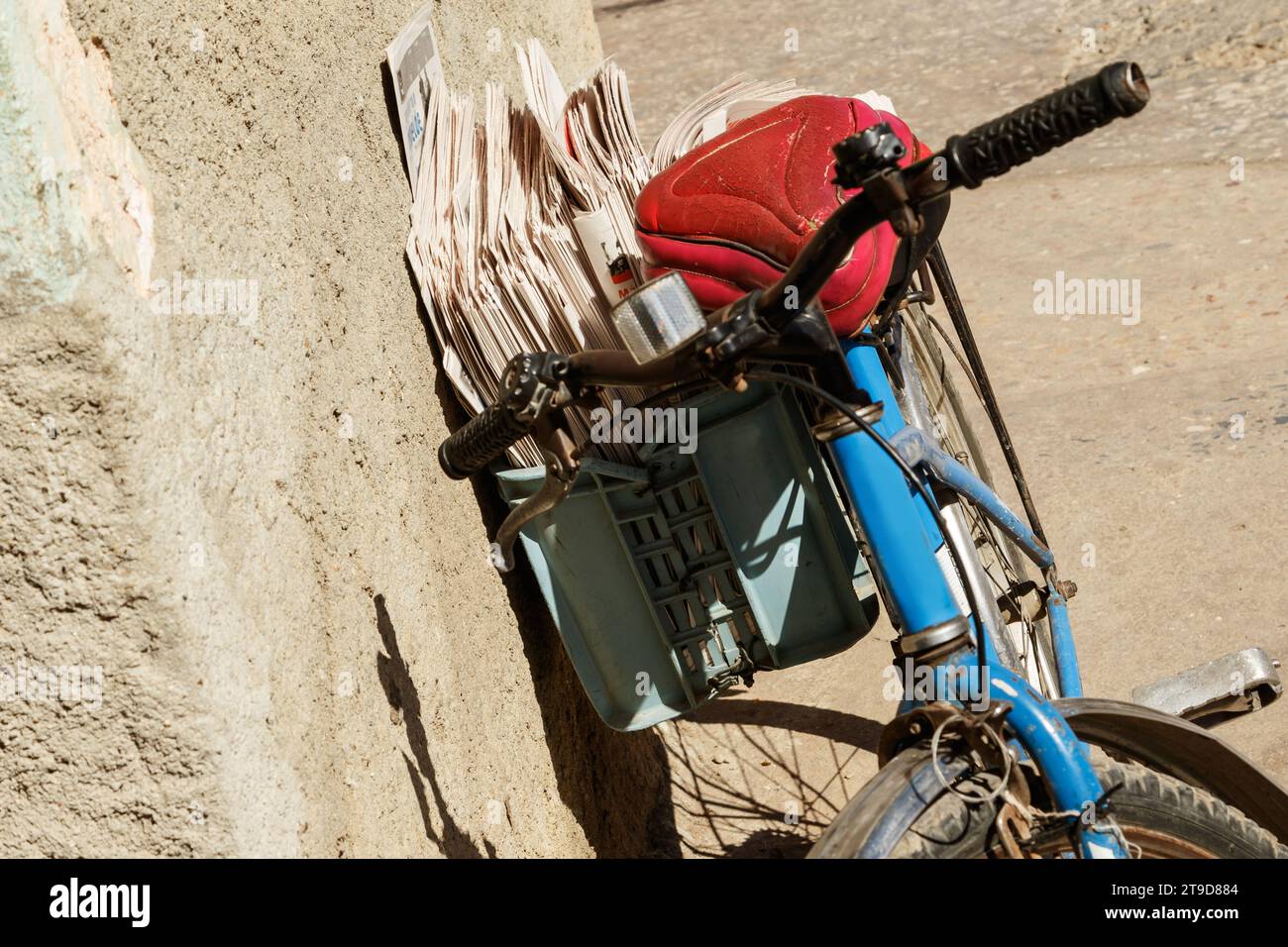 Old postman bicycle loaded with newspapers parked against a stone wall ...