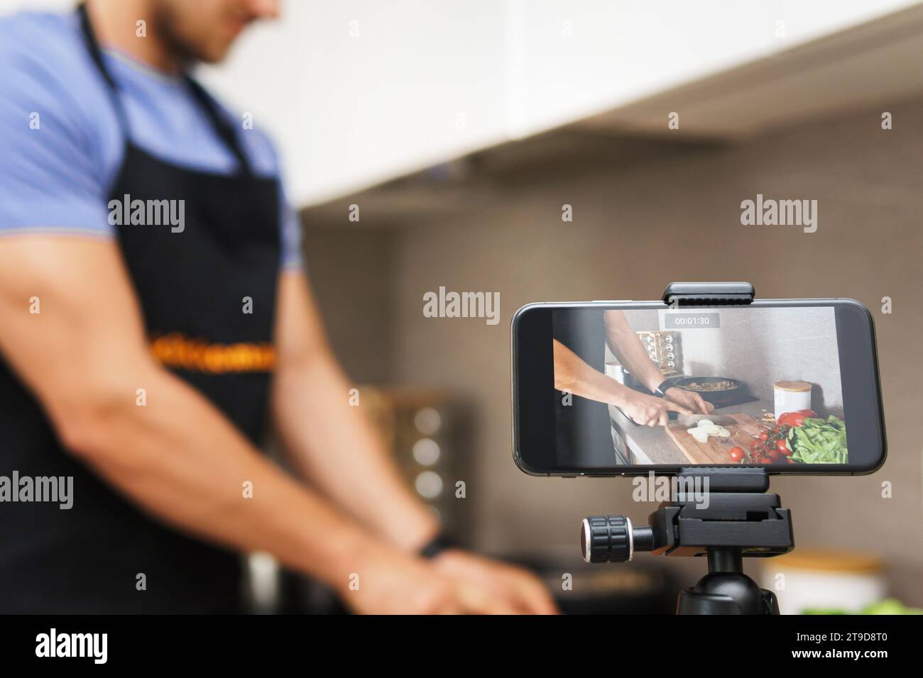 Young bearded chef blogger is cutting onions with a knife on a cutting ...