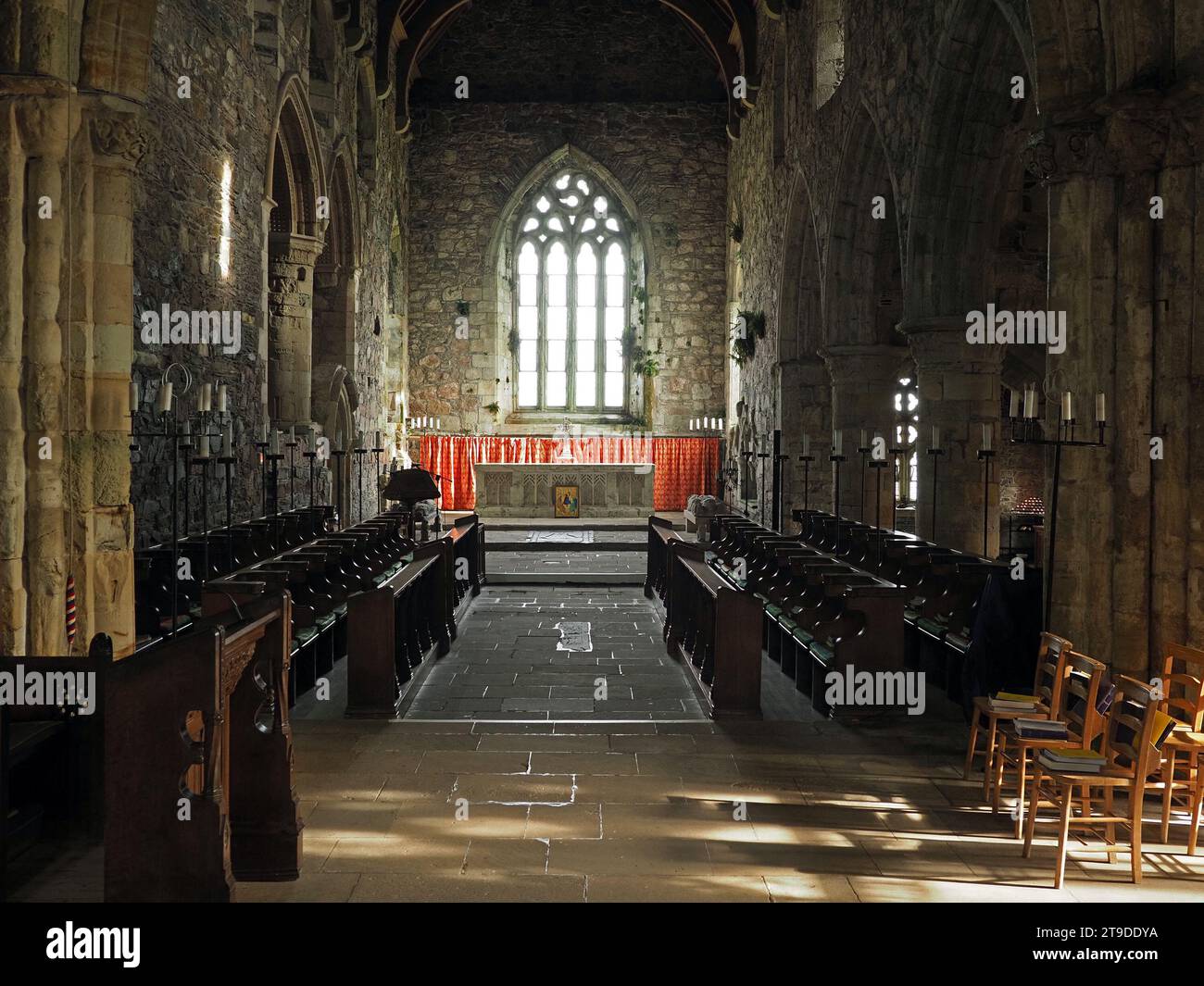 nave & wooden pews of Iona Abbey with light flooding through arched ...