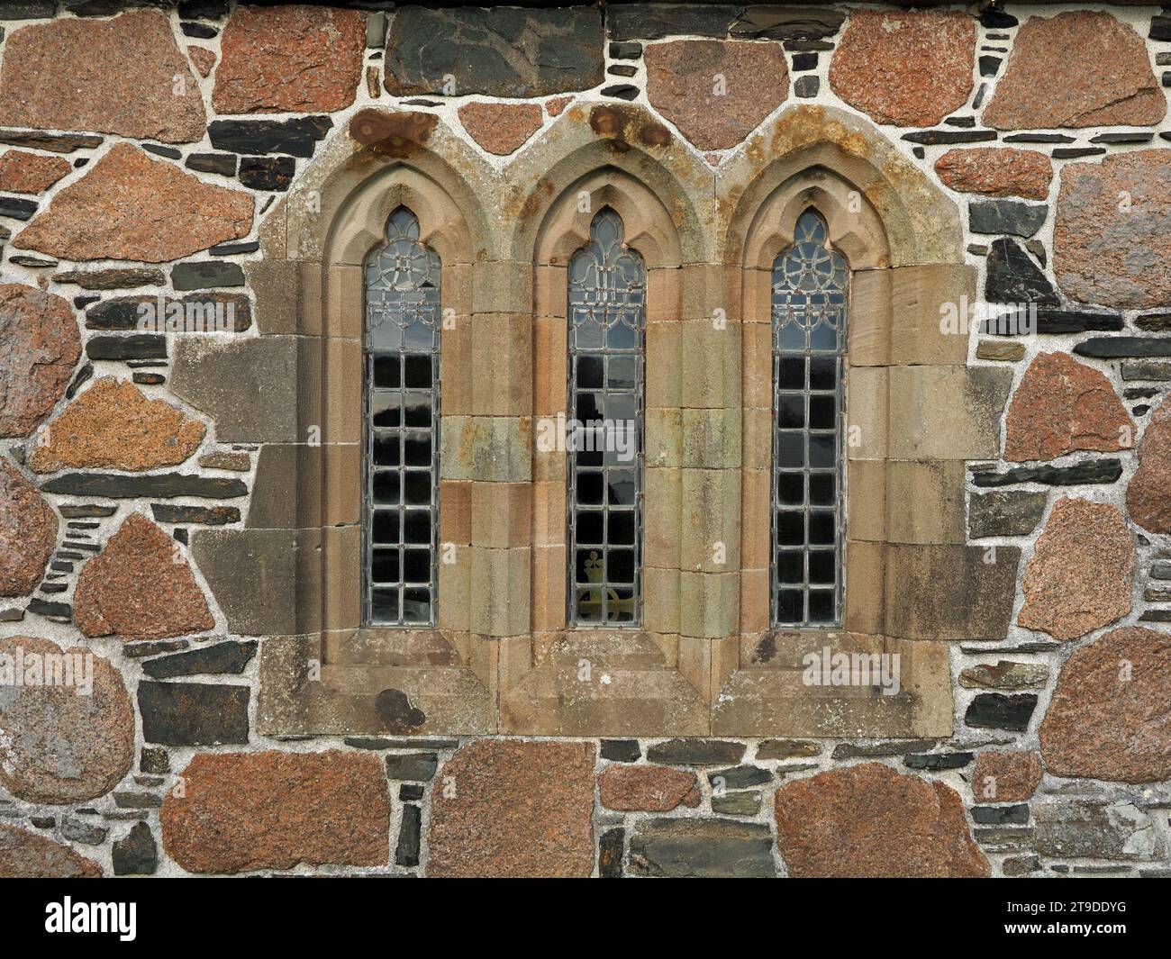 Pattern of irregular stones & 3 narrow mullioned arched windows of ...