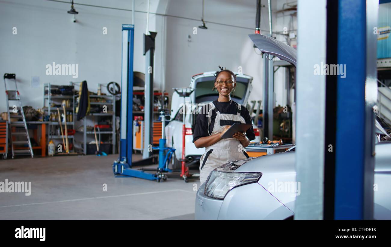 Portrait of cheerful engineer working in professional garage, using ...