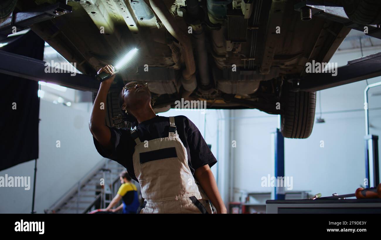 Trained repairman working on suspended car in garage, checking ...
