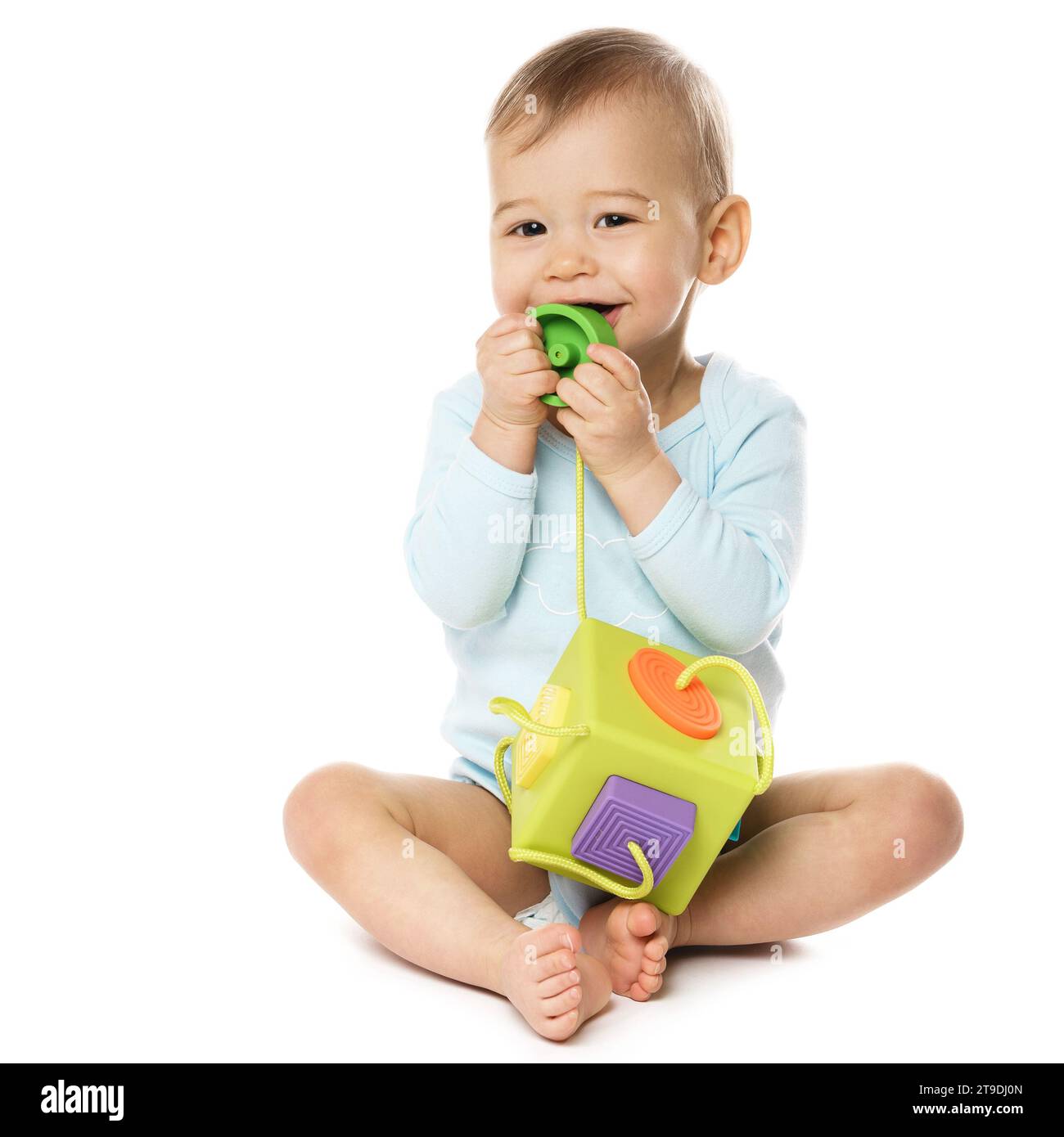 Adorable smiling little boy in a romper is sitting and playing with ...