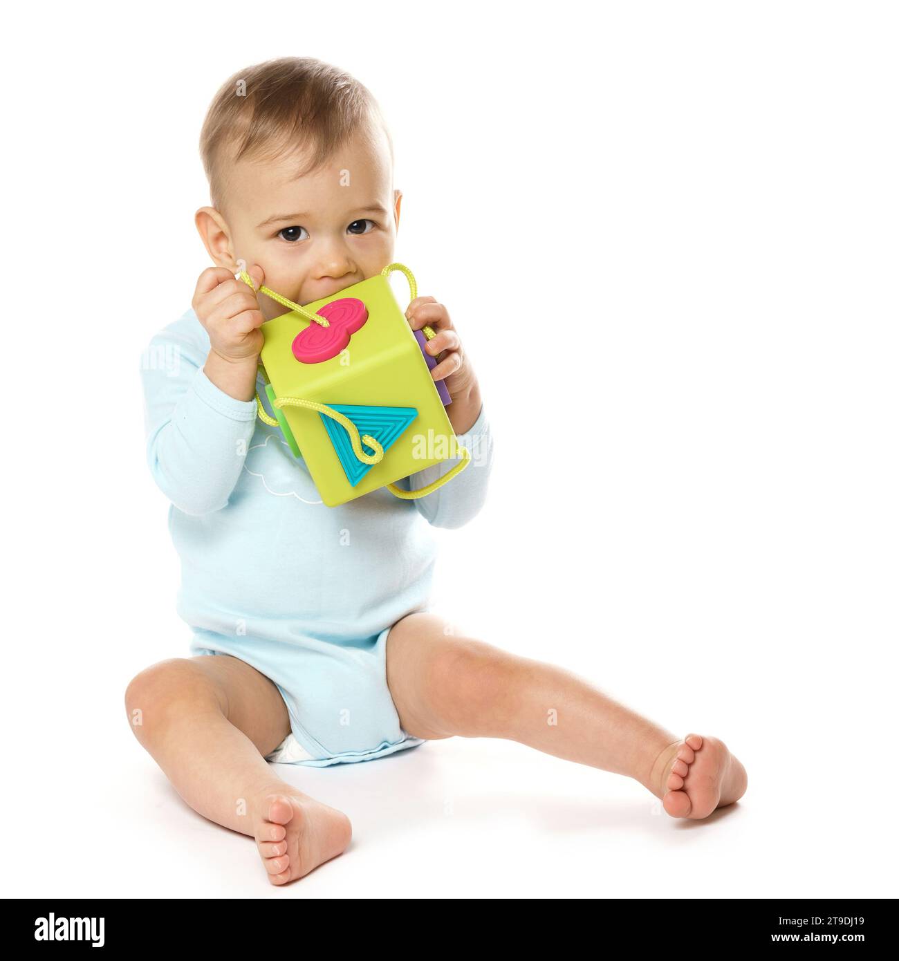 Adorable little boy in a romper is sitting and playing with plastic toy ...