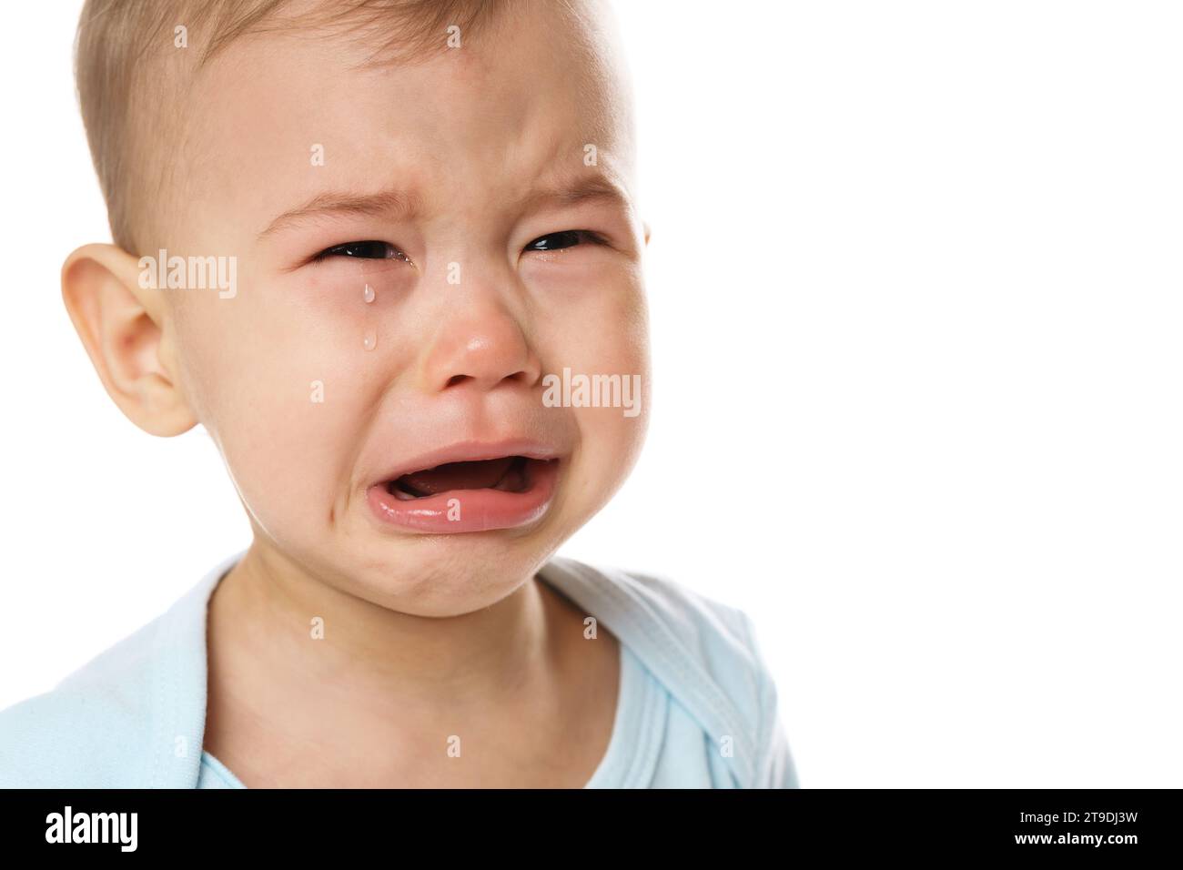 Closeup shot of a face of an adorable crying little boy in a romper on ...