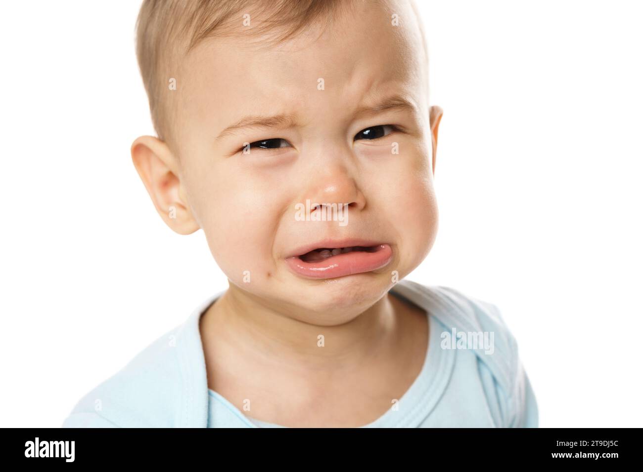 Closeup shot of a face of an adorable crying little boy in a romper on ...