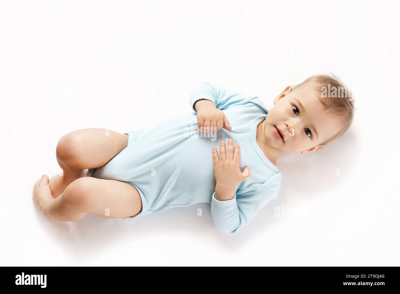 Adorable little boy in a romper is lying on his back and looking. on ...