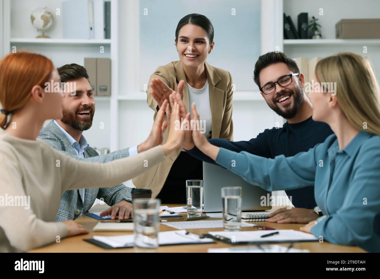 Team of employees joining hands in office Stock Photo - Alamy