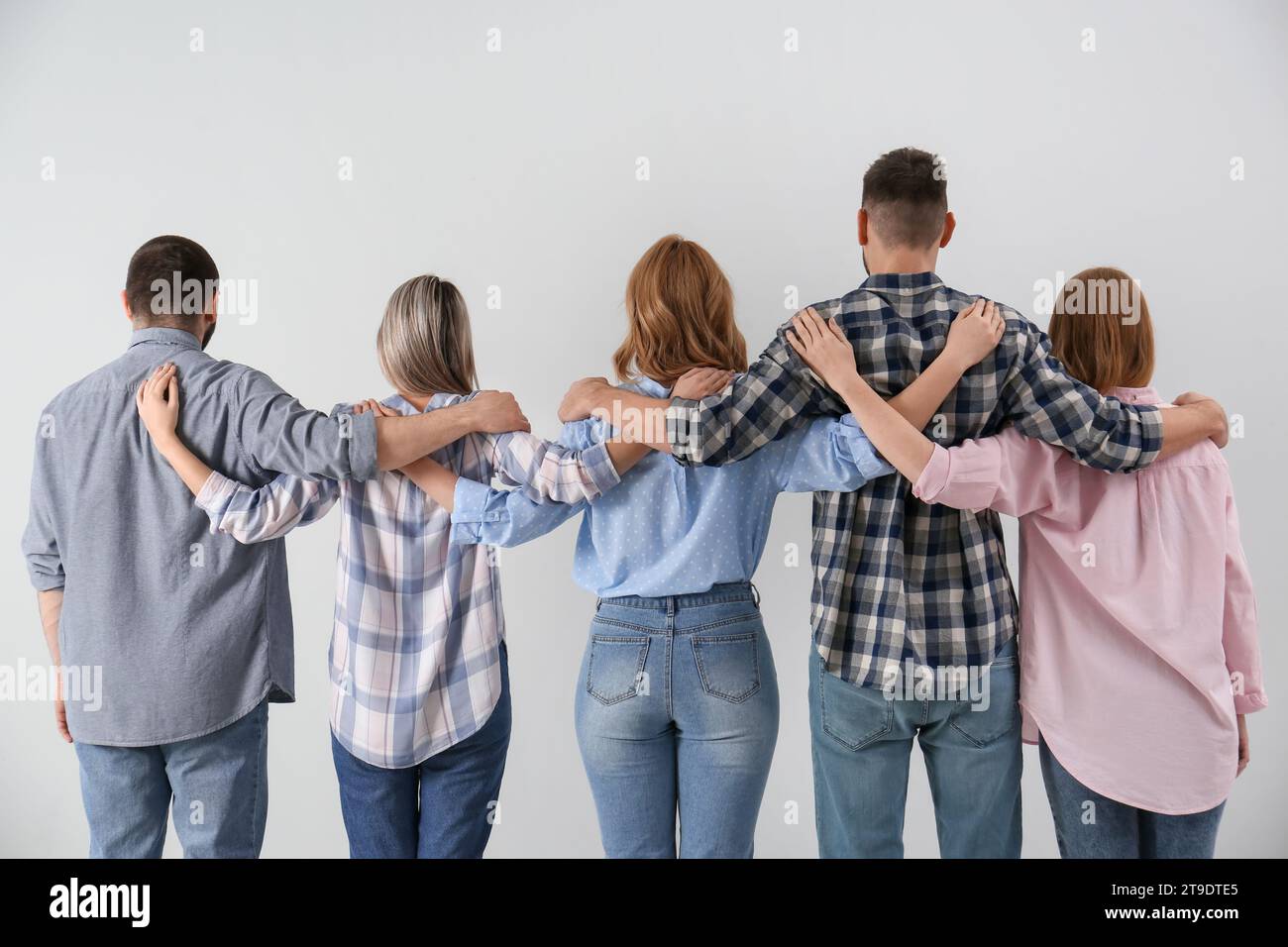 People hugging together on grey background, back view Stock Photo - Alamy