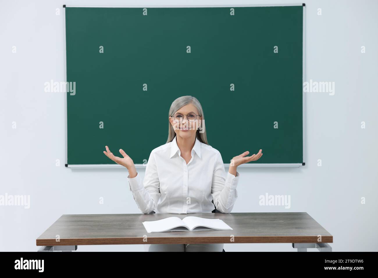 Professor giving lecture at desk in classroom Stock Photo - Alamy