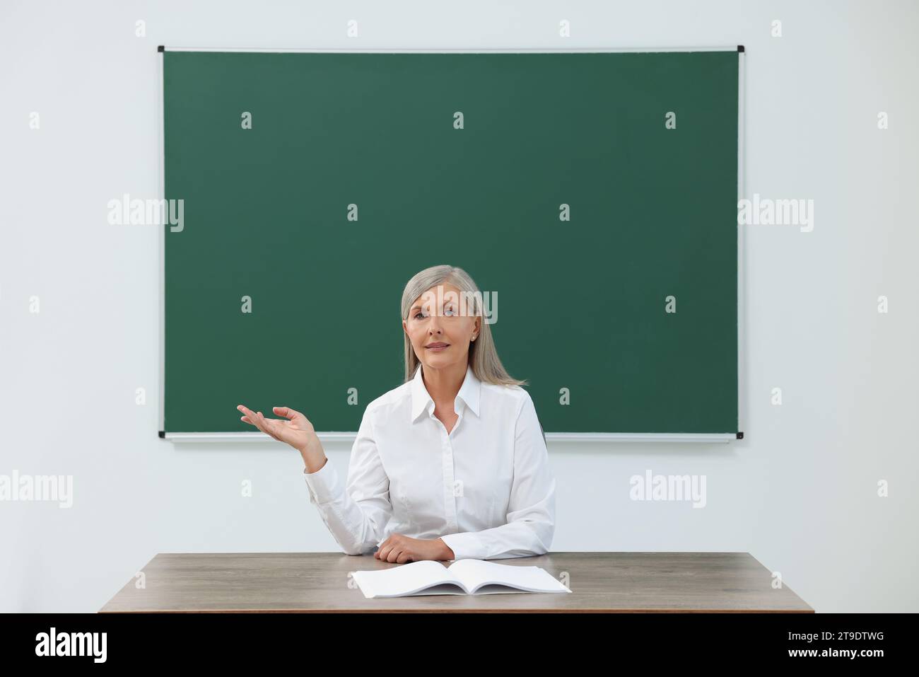 Professor giving lecture at desk in classroom Stock Photo - Alamy
