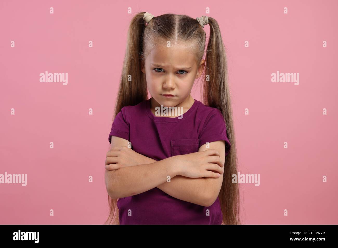Resentful girl with crossed arms on pink background Stock Photo - Alamy