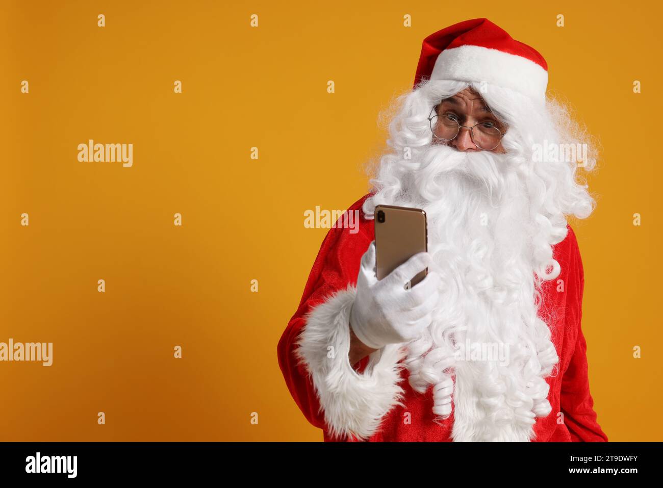 Merry Christmas. Santa Claus using smartphone on orange background ...