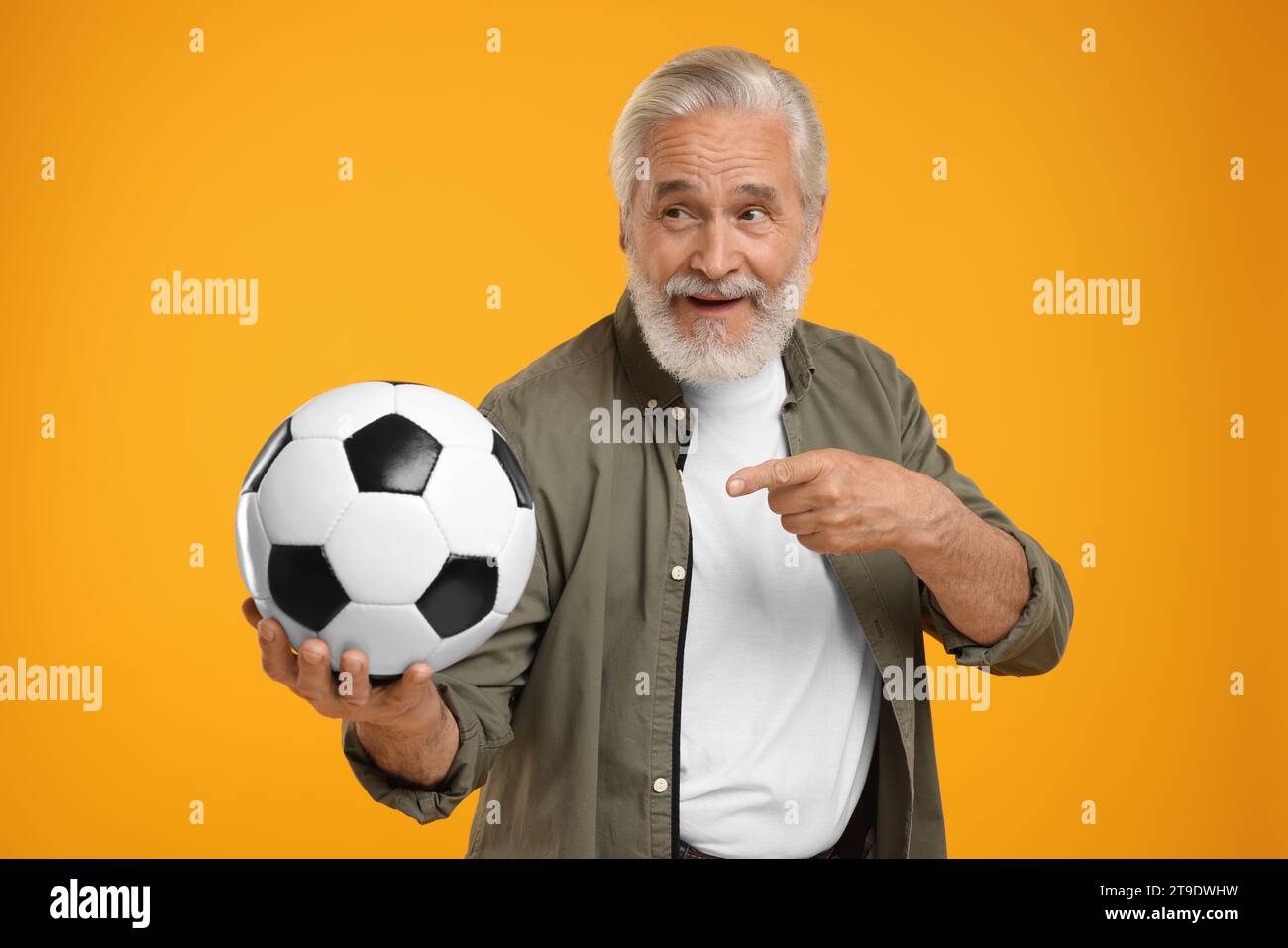 Senior sports fan with soccer ball on yellow background Stock Photo - Alamy