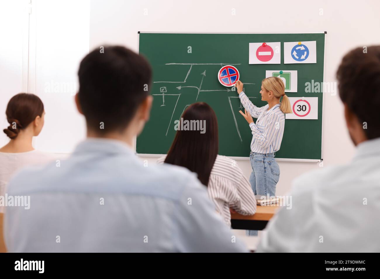 Teacher showing No Stopping road sign near chalkboard during lesson in ...