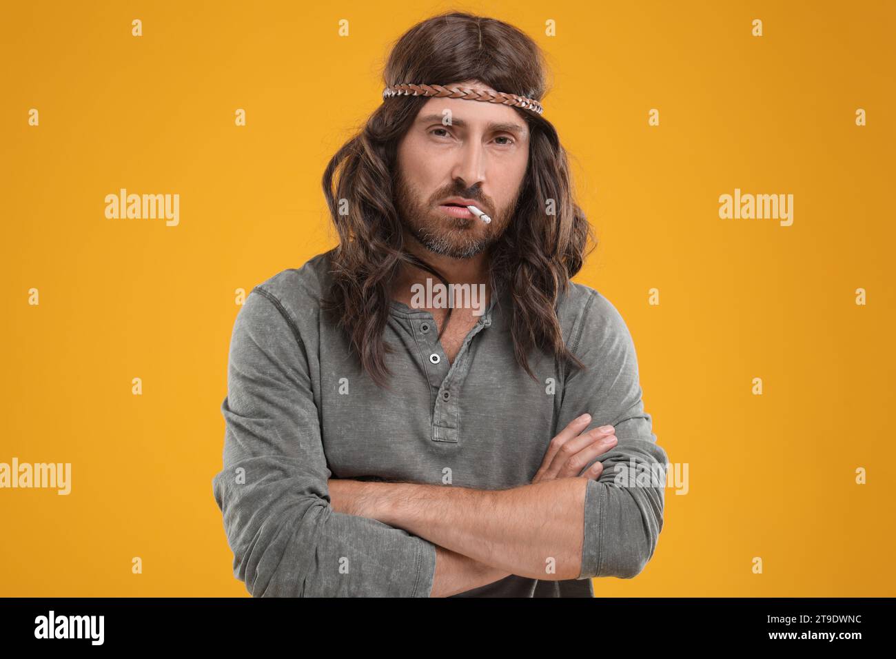 Hippie man smoking cigarette on orange background Stock Photo - Alamy