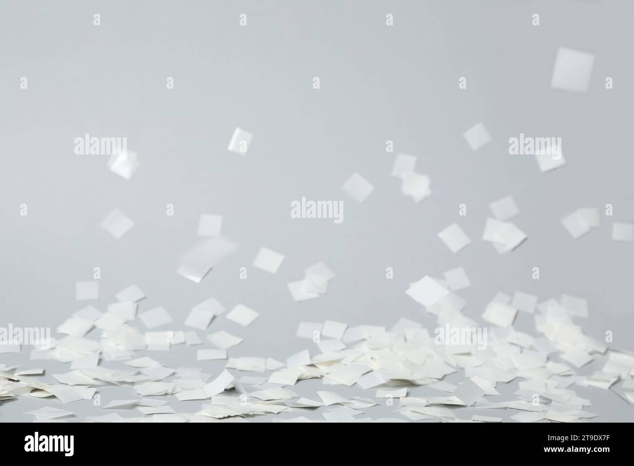 White confetti falling down on light grey background Stock Photo - Alamy