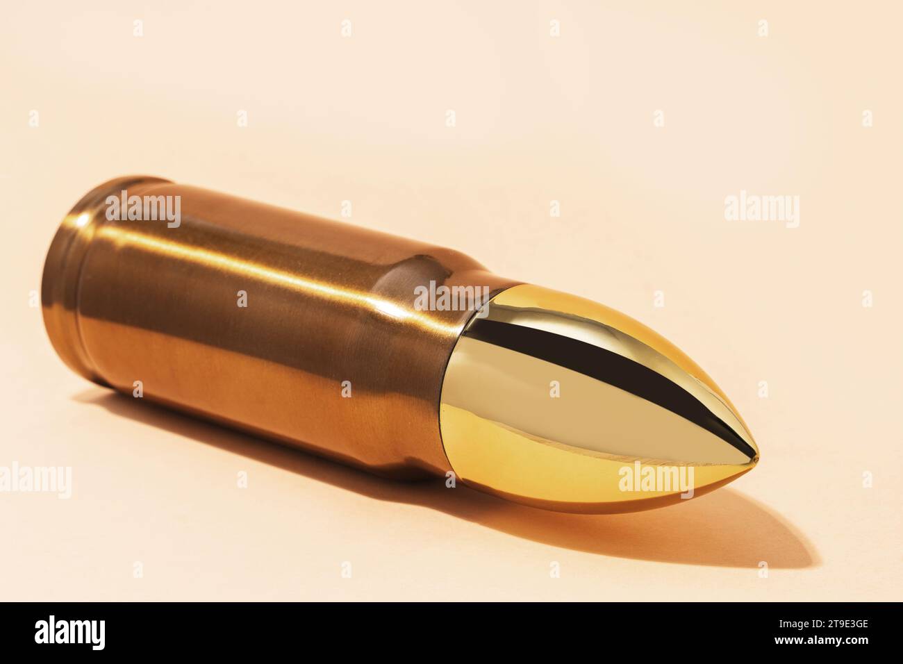 One big shiny bullet against beige background Stock Photo - Alamy