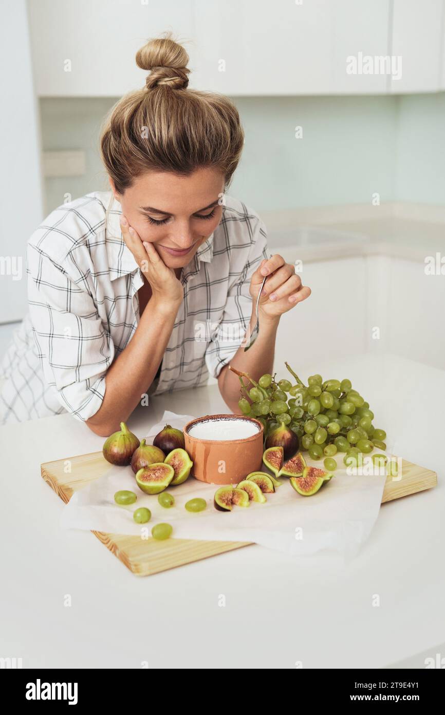Young pretty woman ready to eat her delicious Greek yogurt with figs in ...