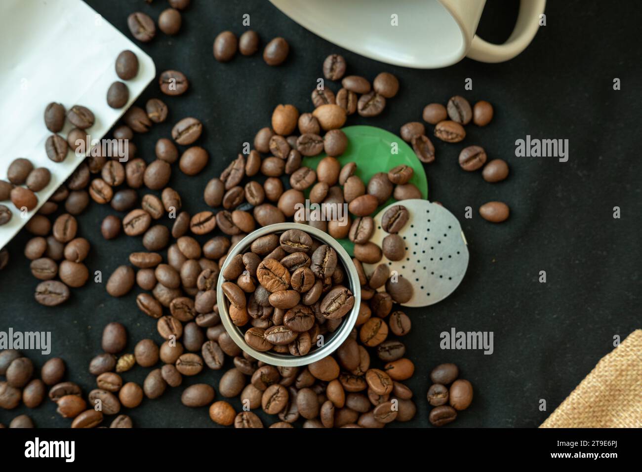 Coffee beans inside and around a refillable coffee capsule on a black ...