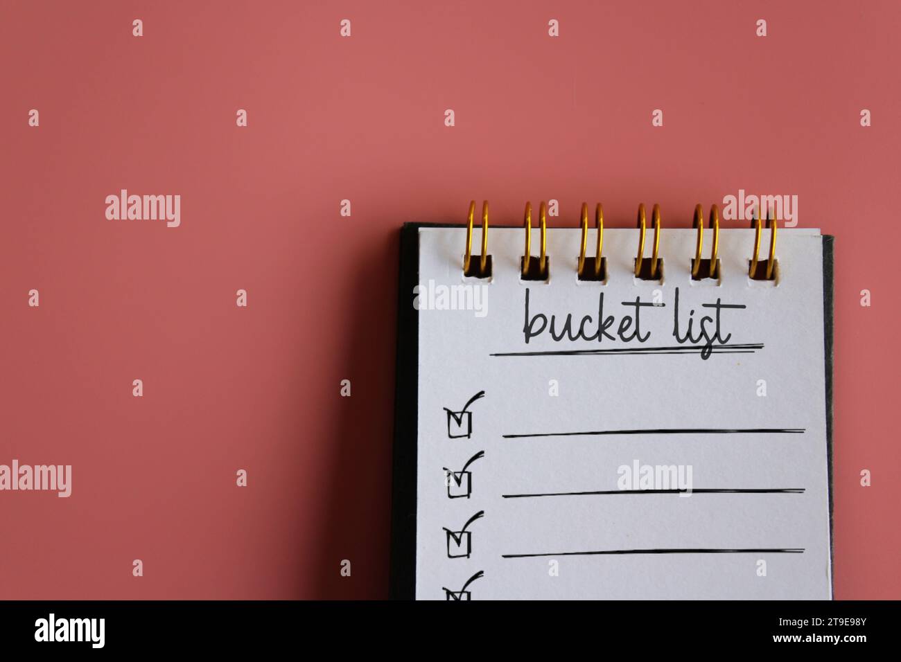 Top view image of notebook with text BUCKET LIST on pink background ...