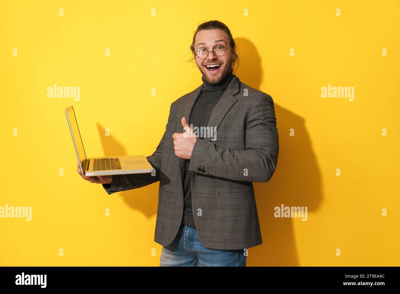 Handsome happy bearded man wearing eyeglasses is using laptop and ...