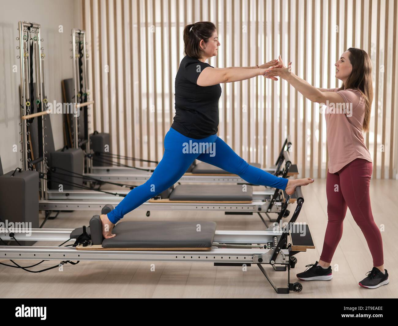 Overweight caucasian woman doing pilates exercises on reformer with ...