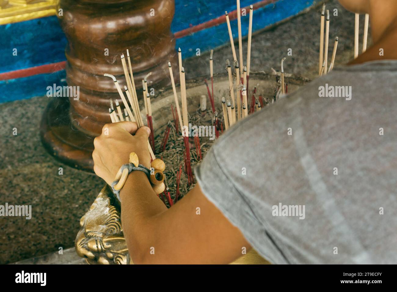 Young female tourist is putting a smoldering stick inside a traditional ...
