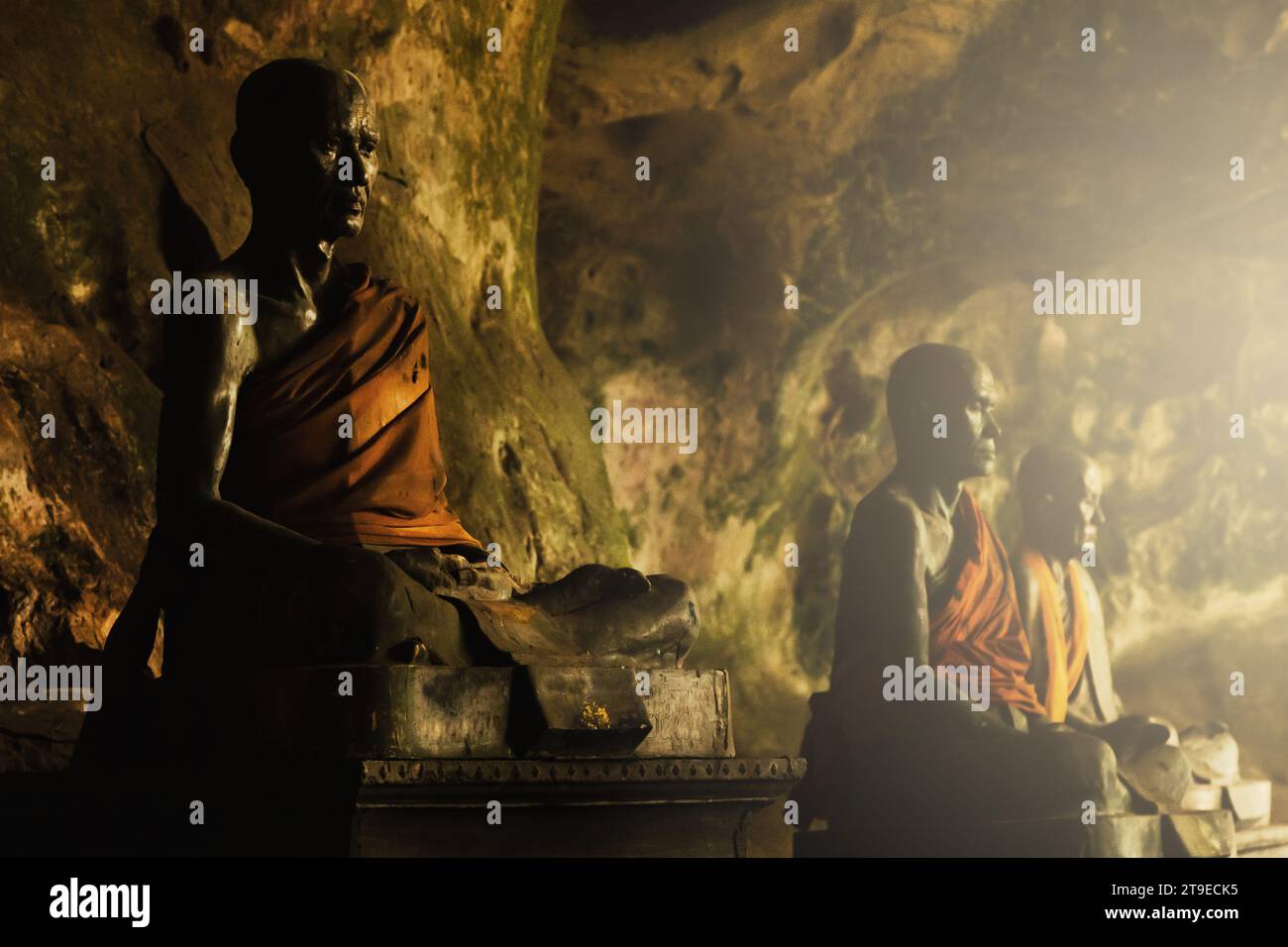 Closeup shot of metallic buddhist monk statues inside a dark cave in ...
