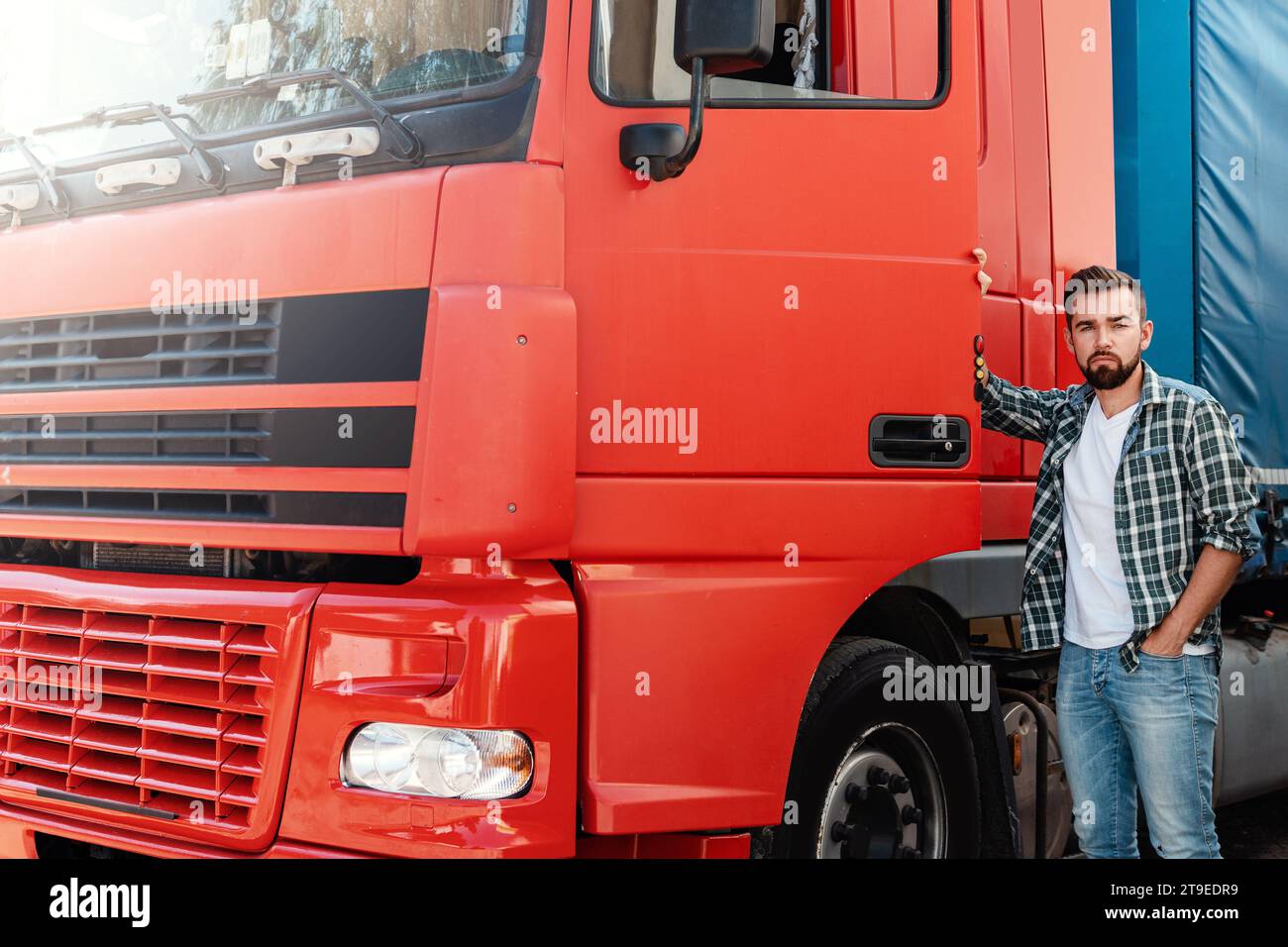 Confident male truck driver standing beside his red cargo truck Stock ...