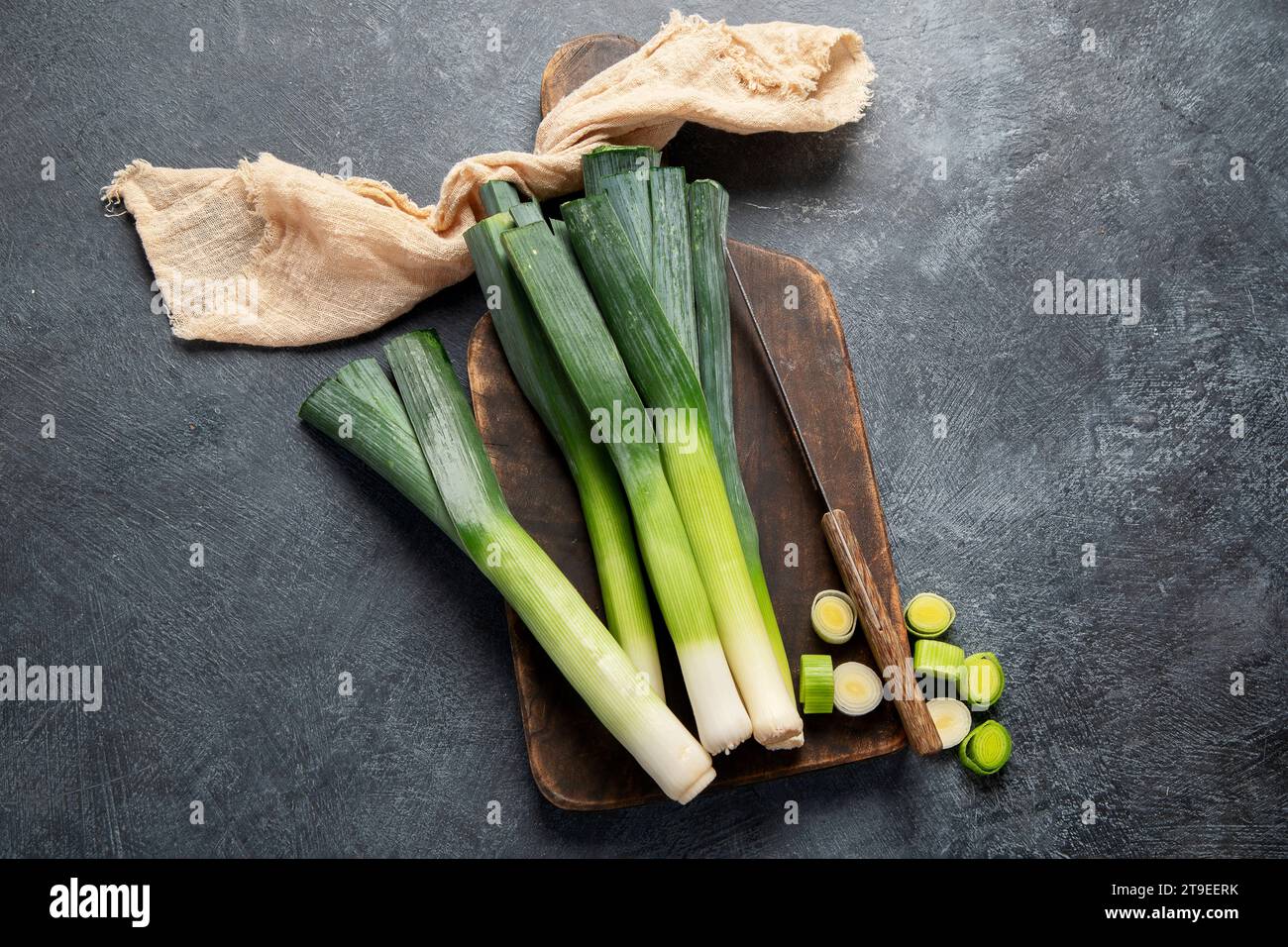 Whole and cut fresh leeks on a dark background, vegetarian food ...