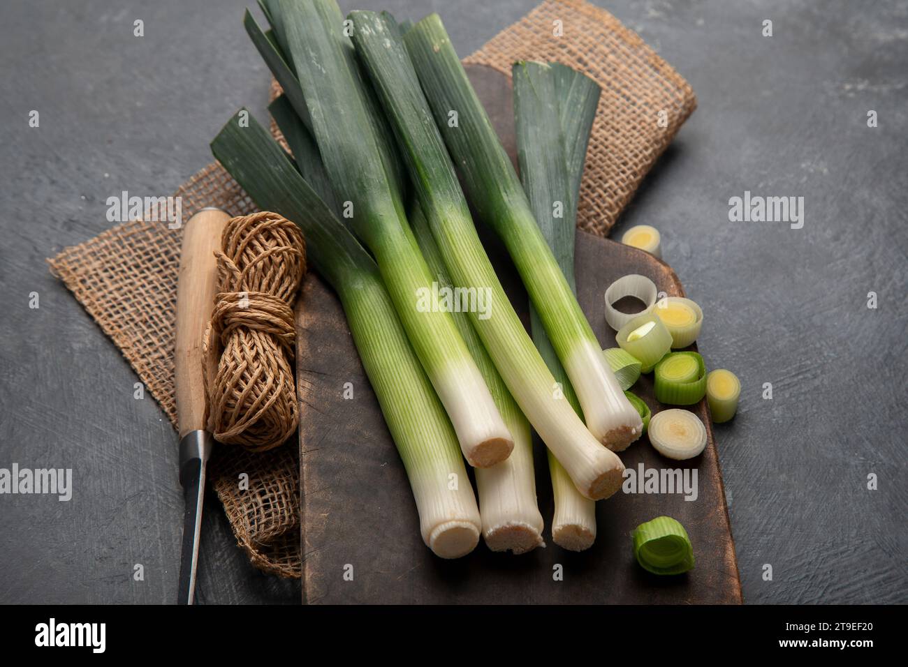 Whole and cut fresh leeks on a dark background, vegetarian food ...