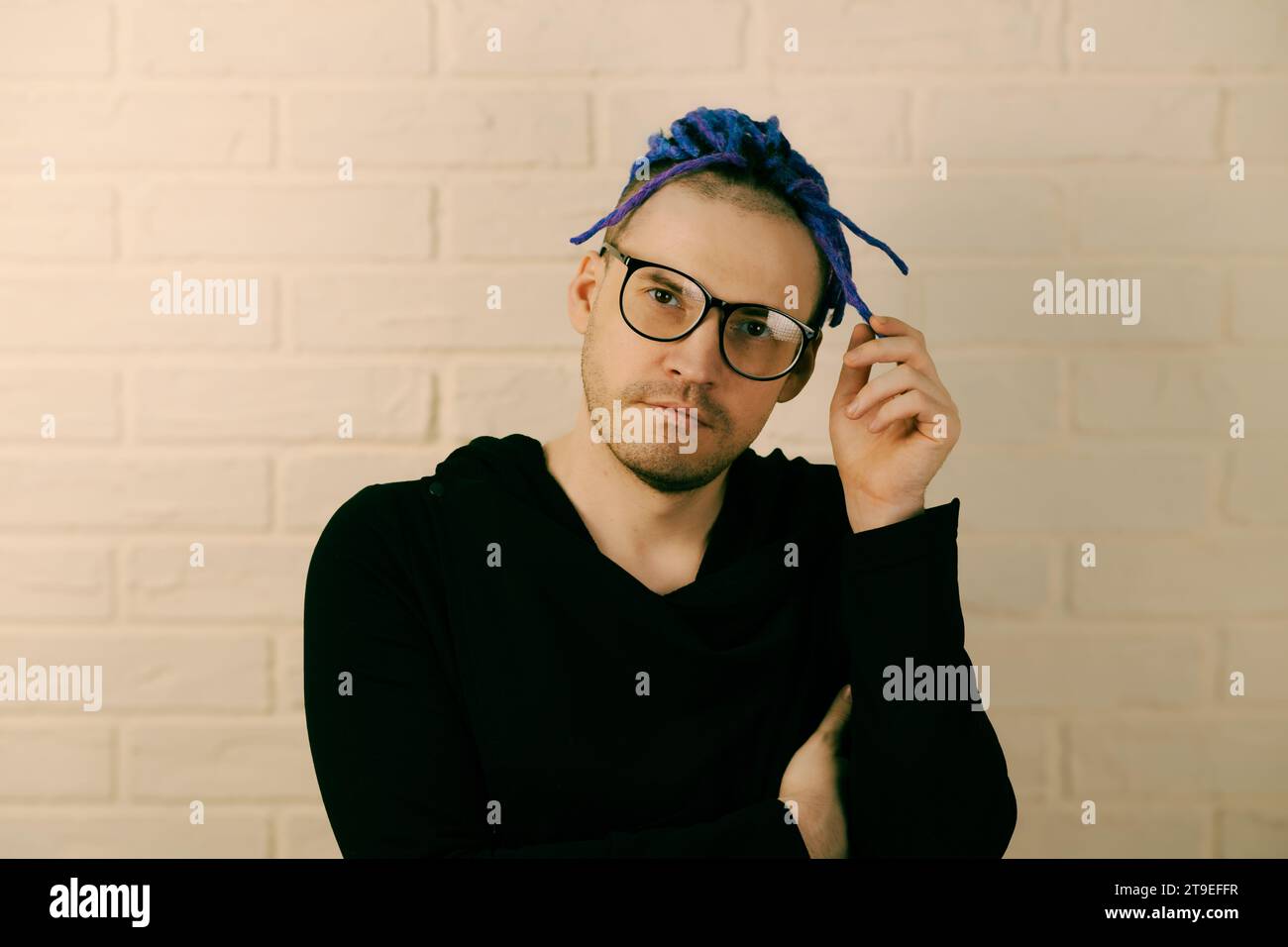 A man with bright purple dreadlocks and glasses twirls dreadlocks in ...