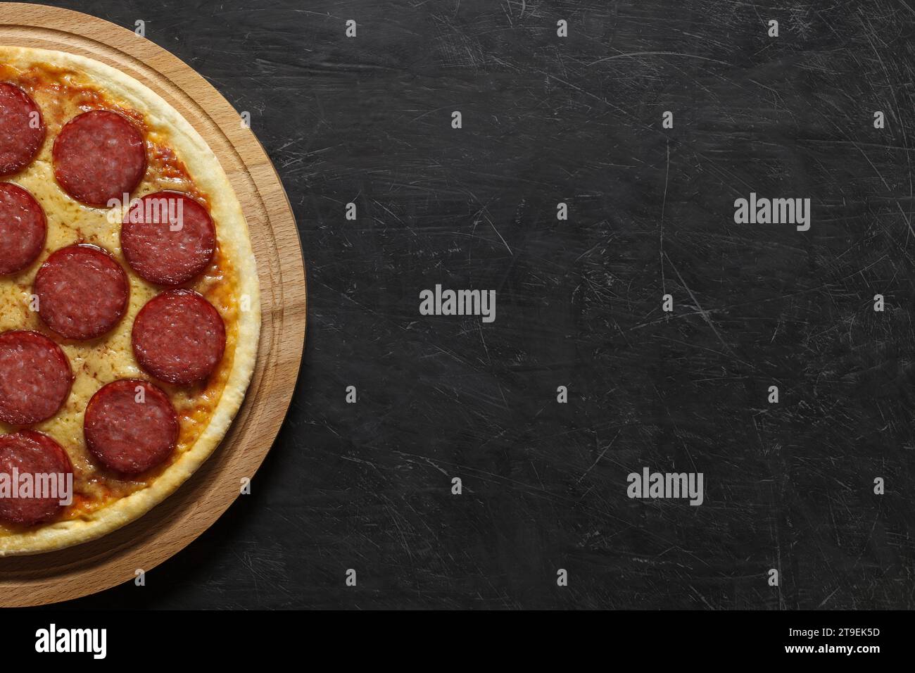 Pepperoni pizza whole uncut, on side on dark background with space to ...