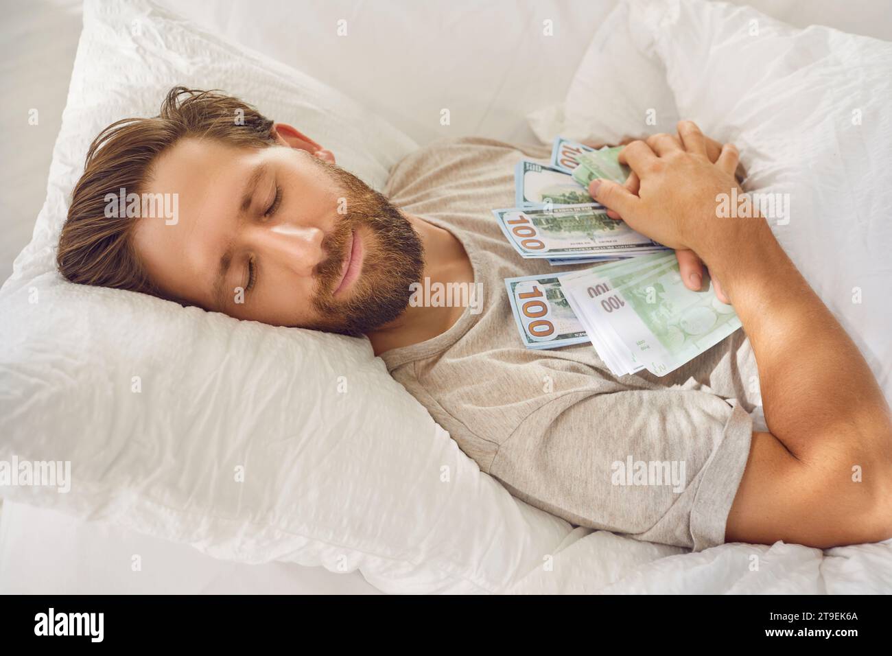 Smiling sleeping man lying in bed with closed eyes, embracing lots of ...