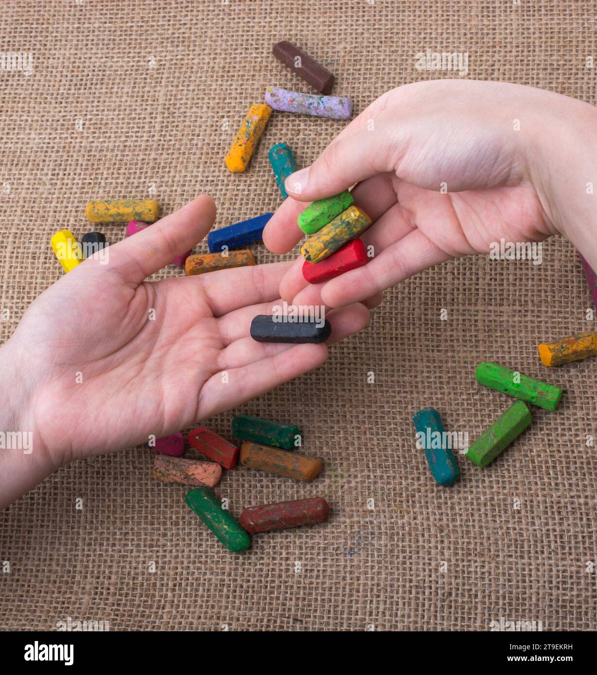 Used color crayons and a hand giving out some Stock Photo - Alamy