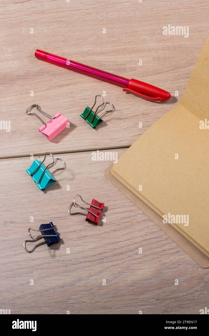 Brown color notebook, pen and paper clips on wooden texture Stock Photo ...