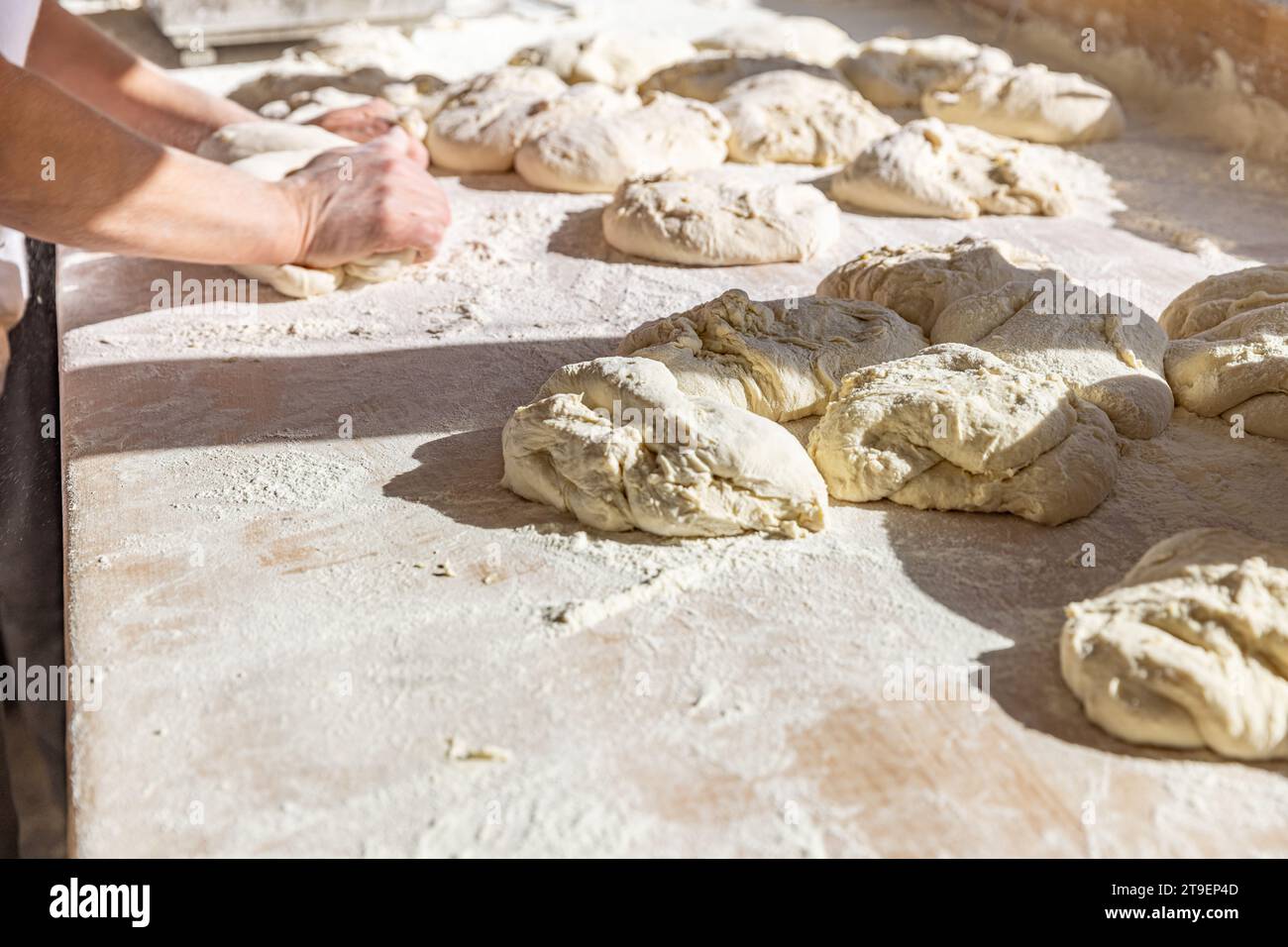 Bakers standing at a work table and molding the bread Stock Photo - Alamy