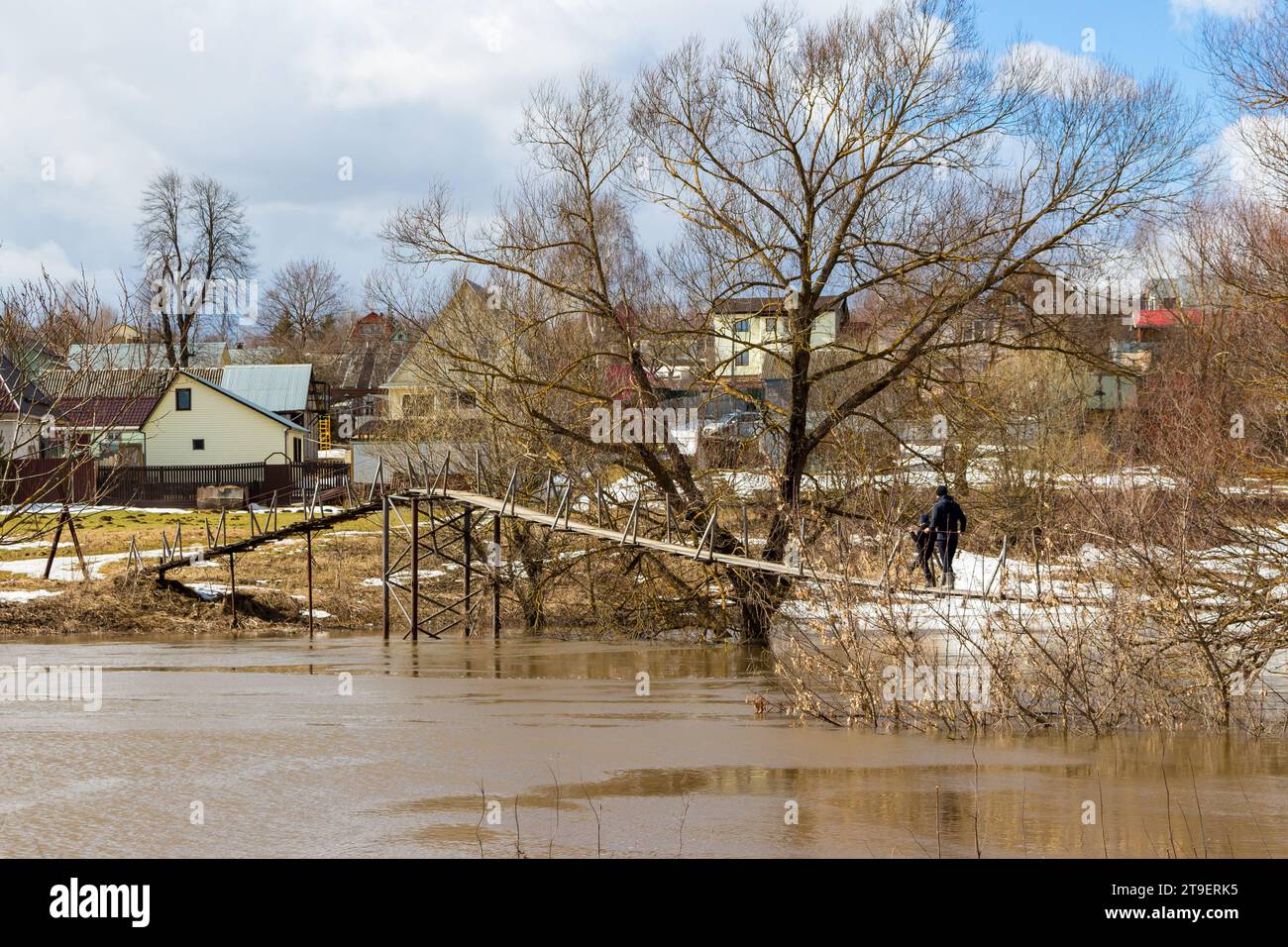 Suspension pedestrian bridge in the countryside during spring flood ...