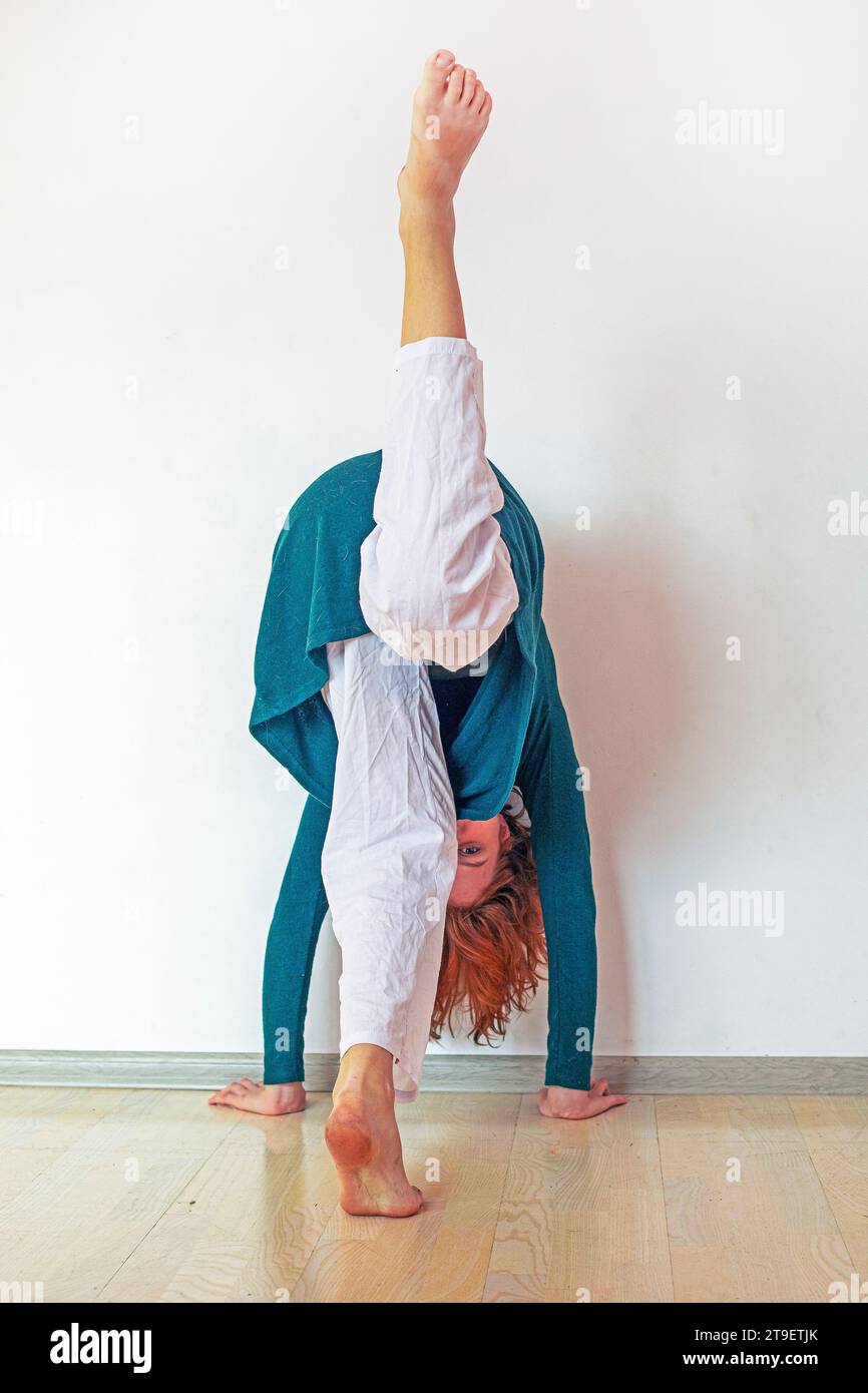 teenage girl practicing doing a handstand near the wall in her room ...