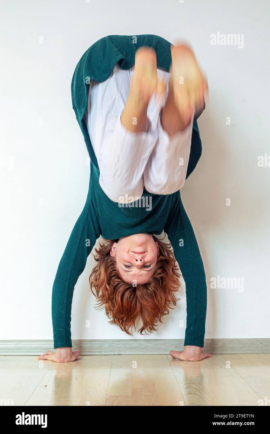 teenage girl practicing doing a handstand near the wall in her room ...