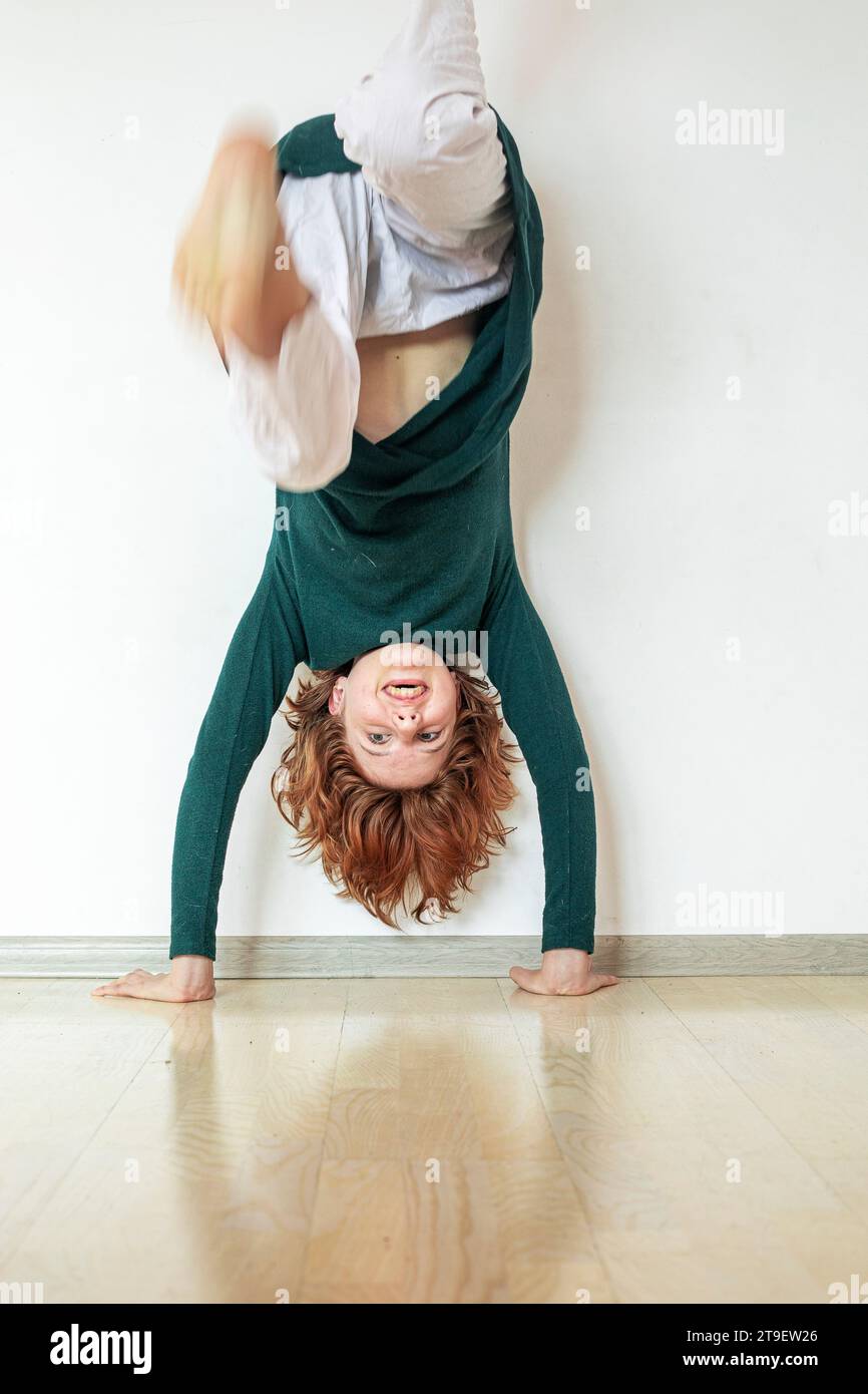 teenage girl practicing doing a handstand near the wall in her room ...